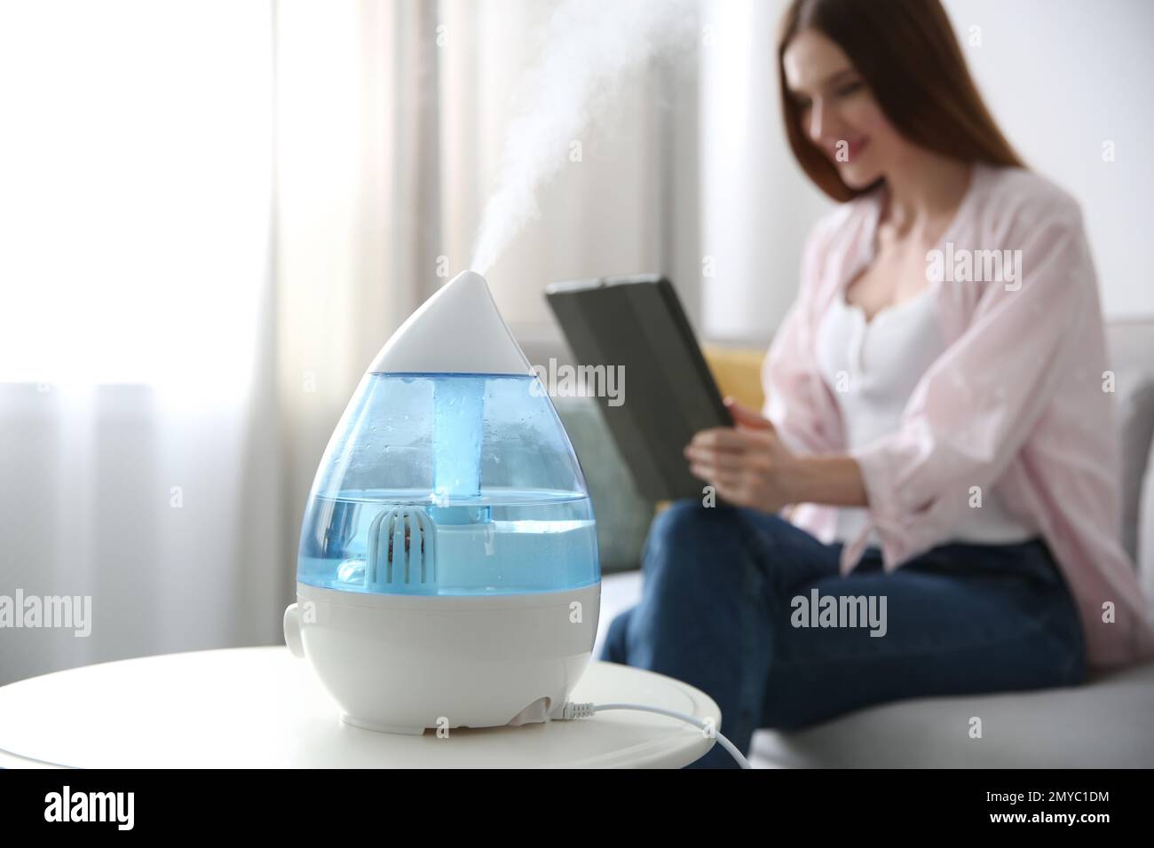 Modern air humidifier and blurred woman on background Stock Photo - Alamy