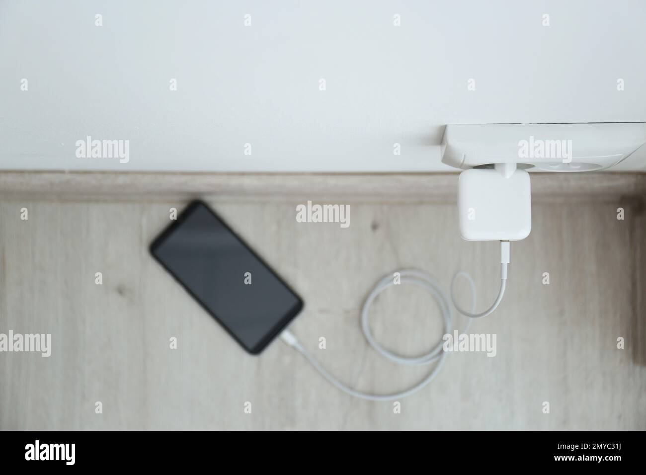 Modern mobile phone charging from electric socket, top view Stock Photo ...