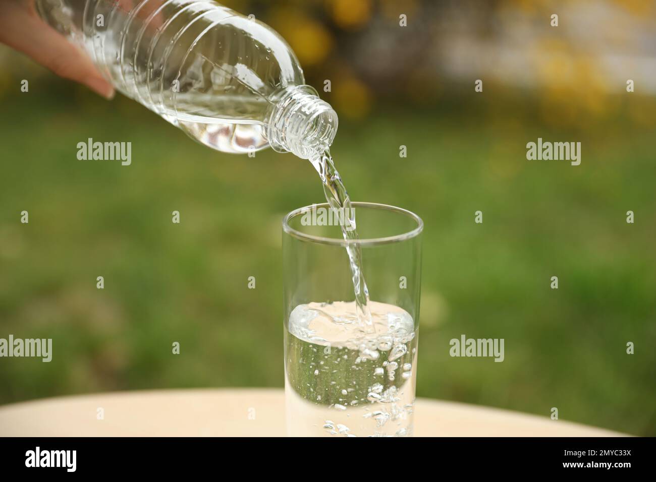 Woman pouring water from bottle into glass outdoors, closeup Stock Photo - Alamy