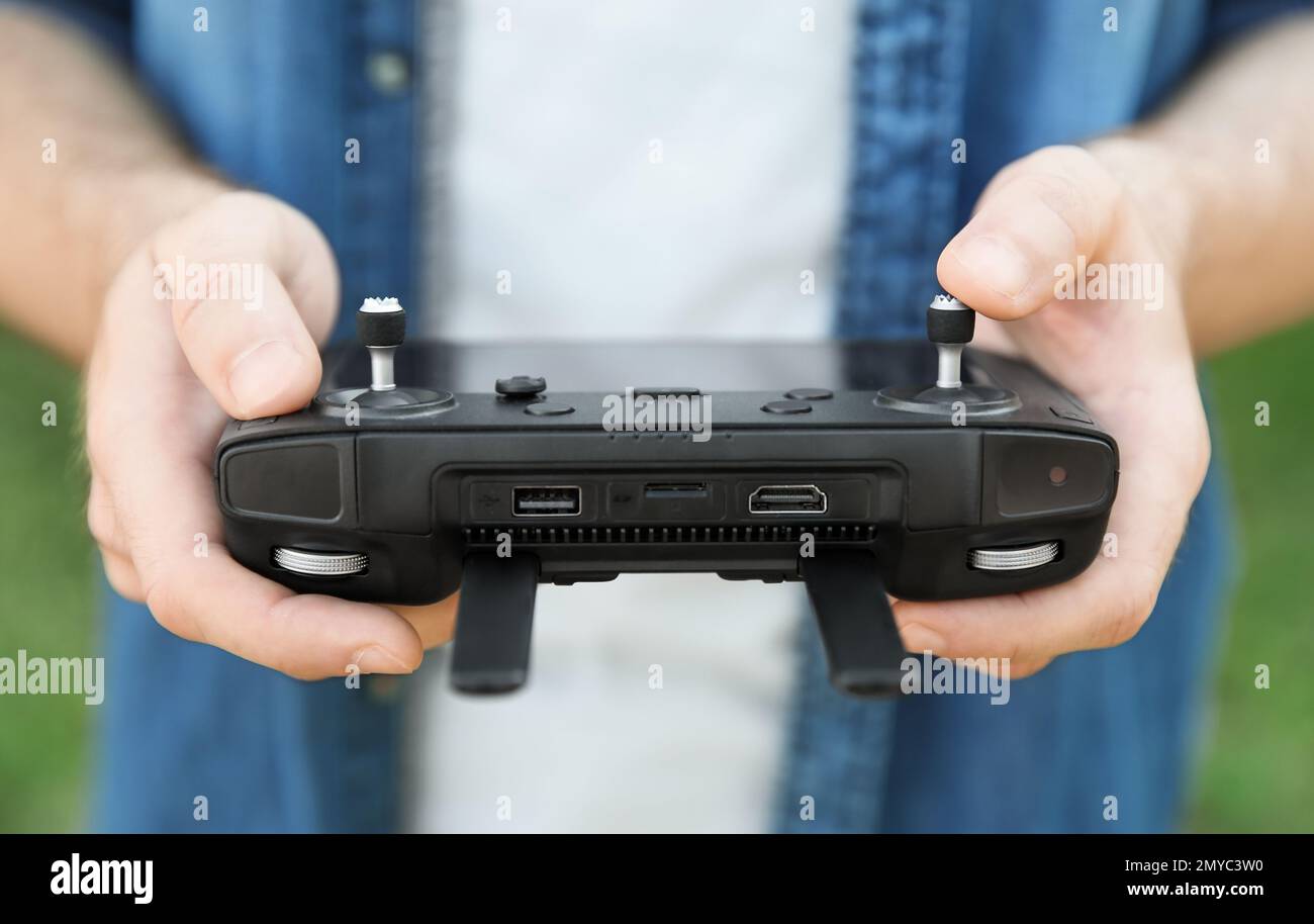 Man holding new modern drone controller outdoors, closeup of hands ...