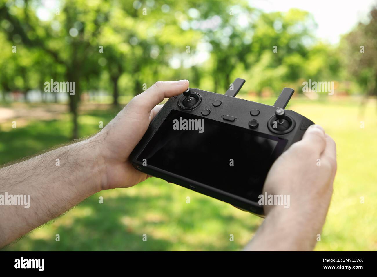 Man holding new modern drone controller outdoors, closeup of hands ...