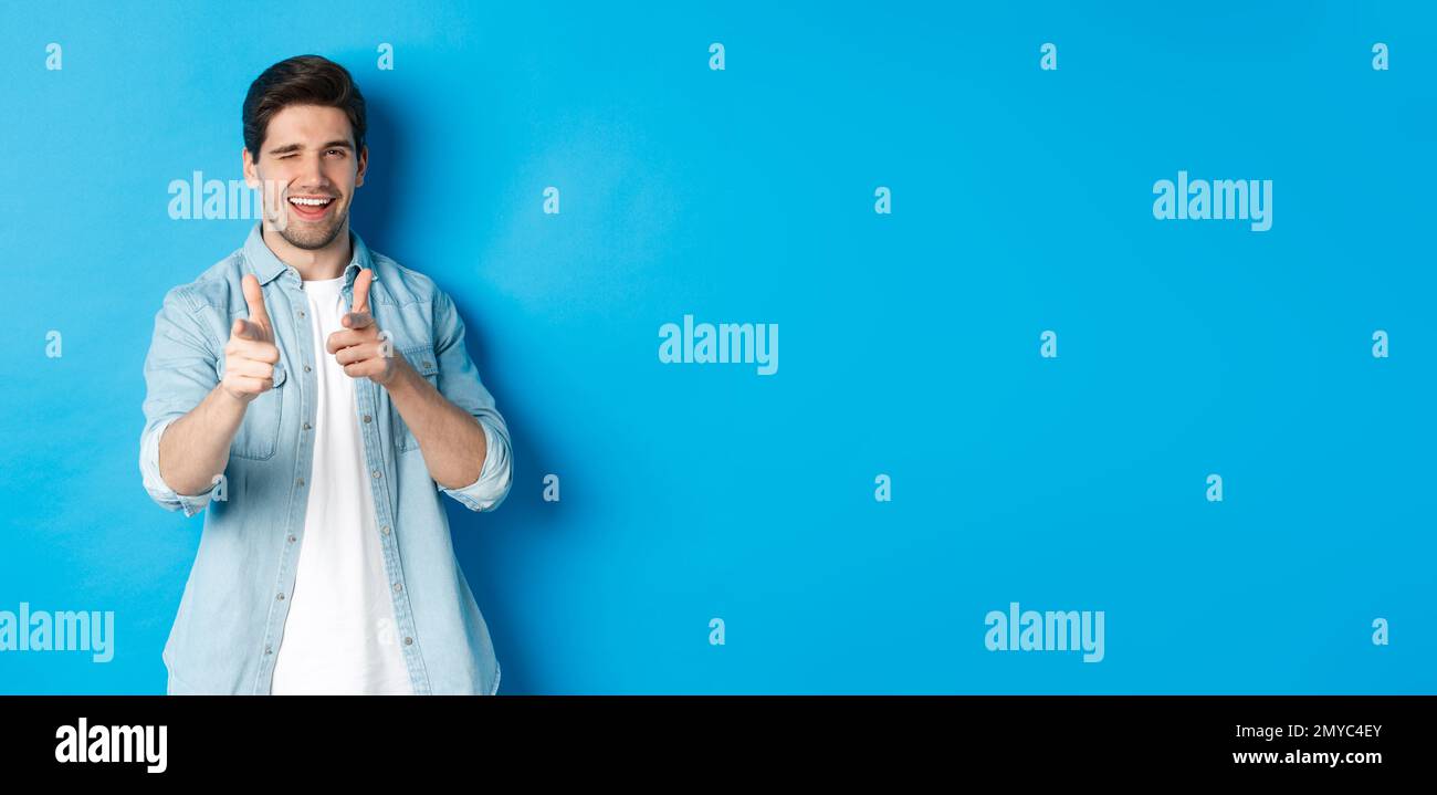 Cheeky handsome guy pointing fingers at you, winking flirty, standing ...