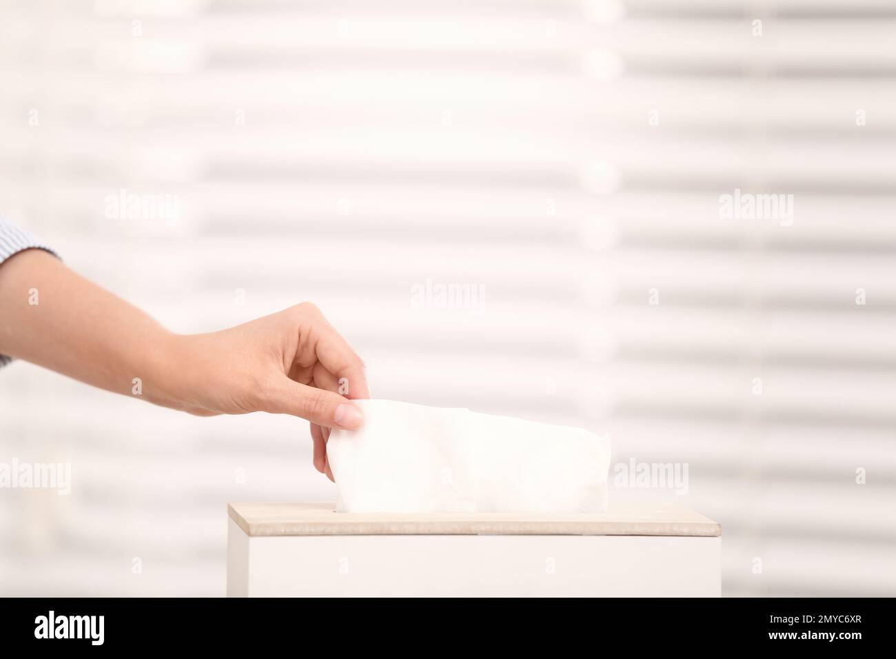Woman taking paper tissue from holder on light background, closeup ...