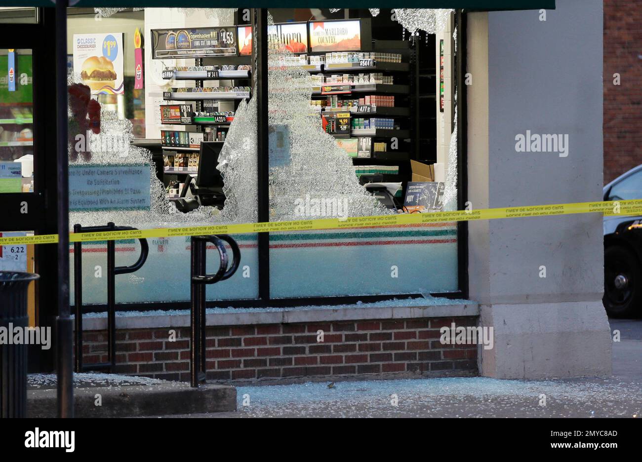 Broken glass from windows shot out at a store litter the street ...