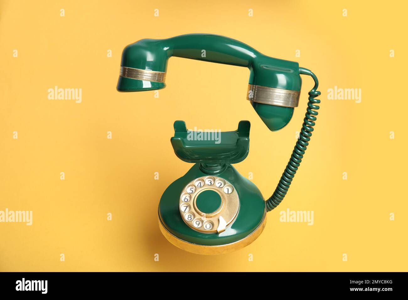 Green vintage corded phone on yellow background Stock Photo - Alamy