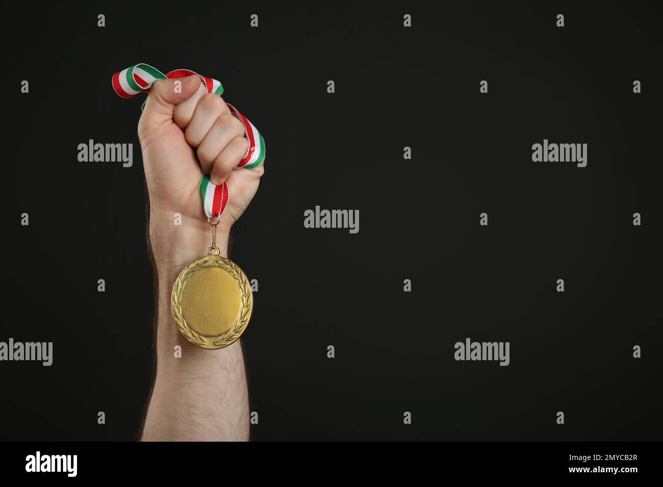 Man holding golden medal on black background, closeup. Space for design ...
