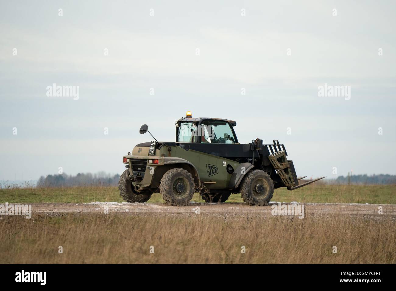 British army JCB fork lift truck driving a dirt track on a military ...