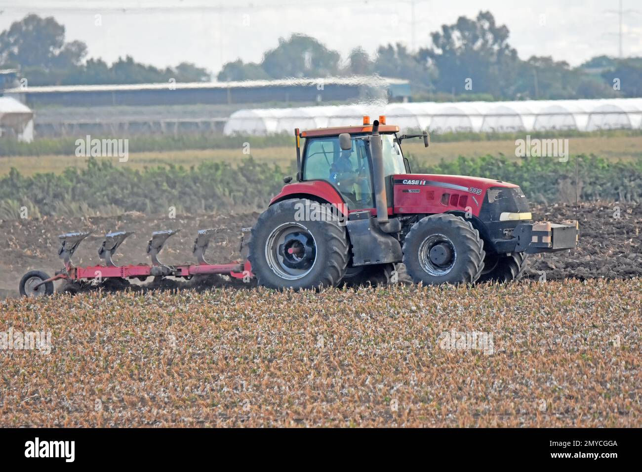 Red tractor plowing a field Stock Photo - Alamy