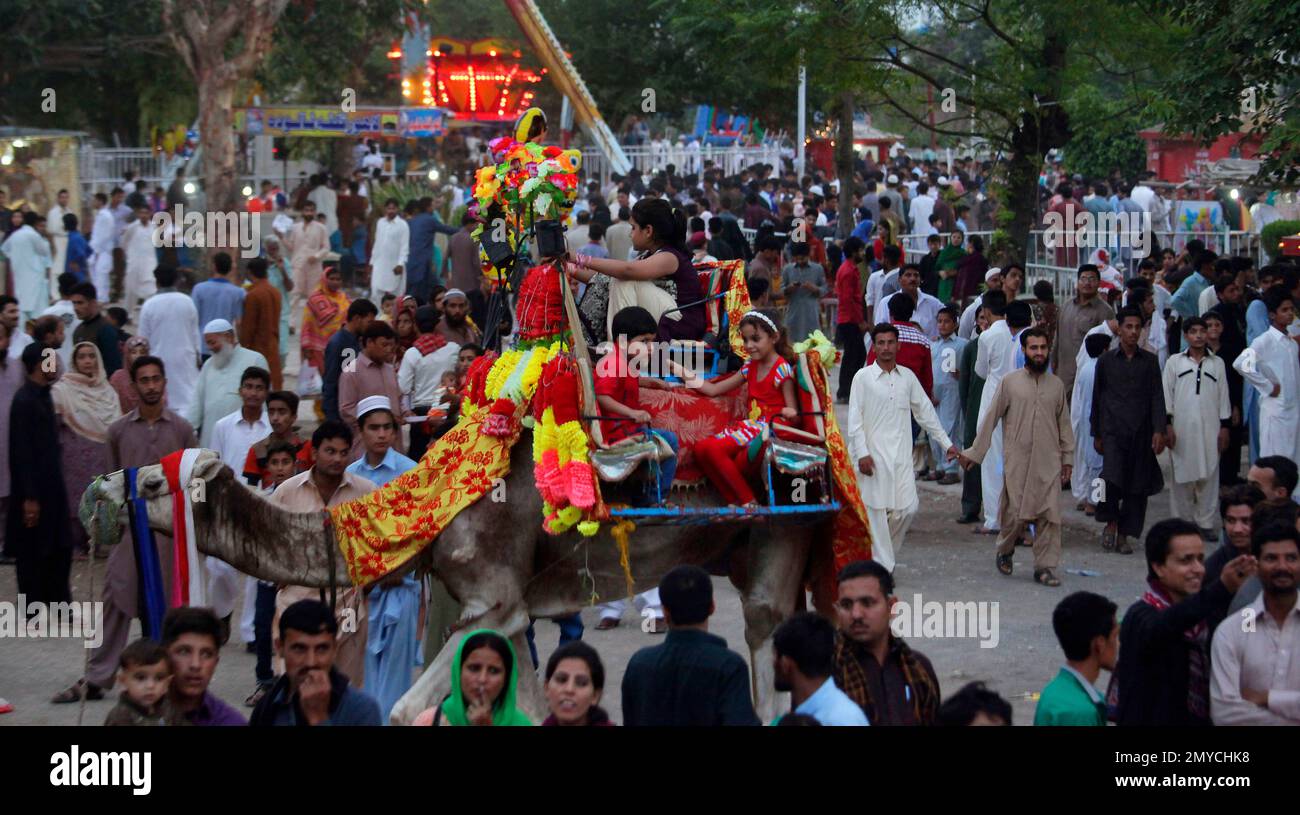 Pakistani children enjoy a camel ride at a fair to celebrate the Eid al ...