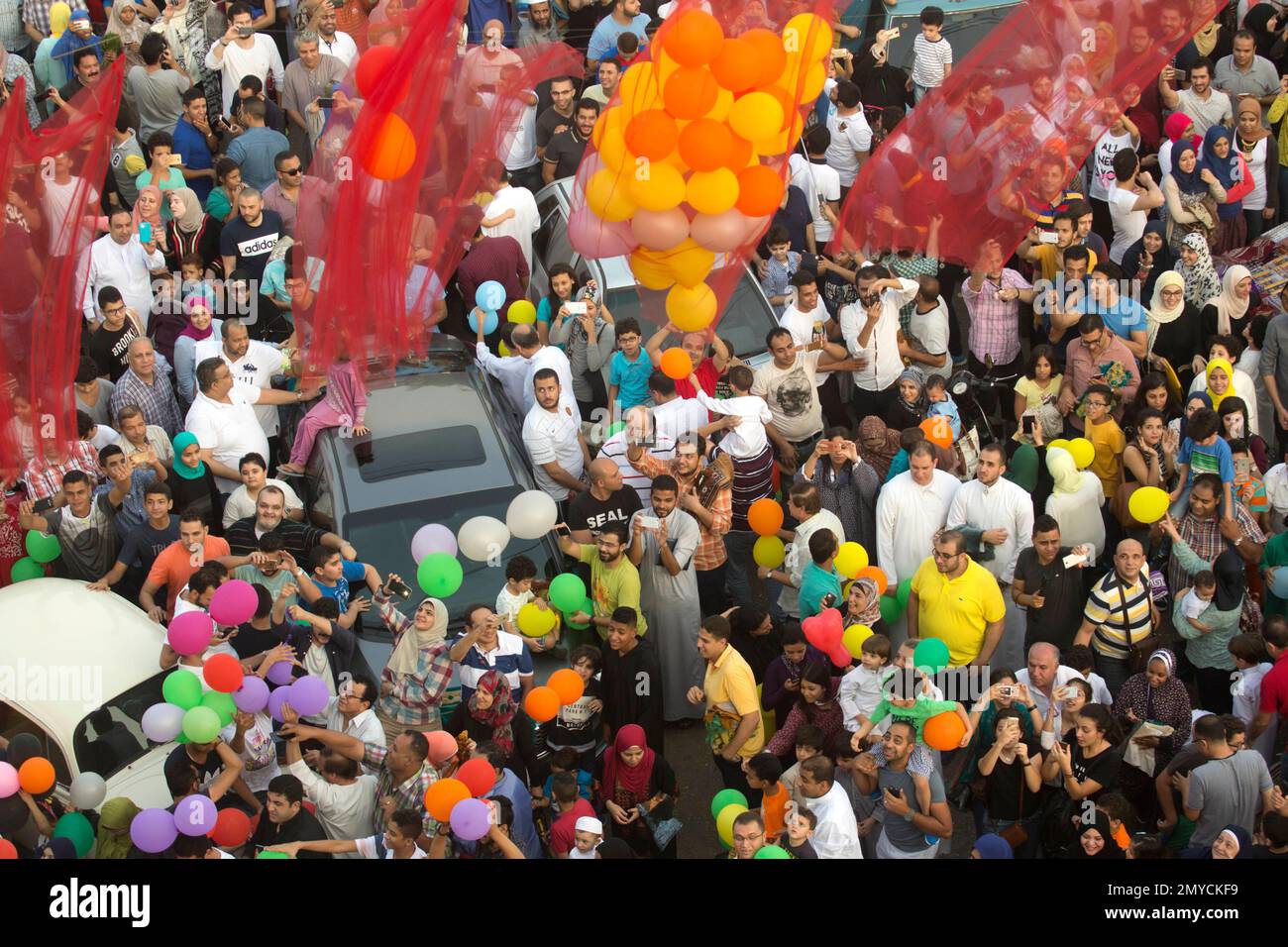 Egyptians wait to catch balloons distributed after Eid al-Fitr prayers, marking the end of the ...