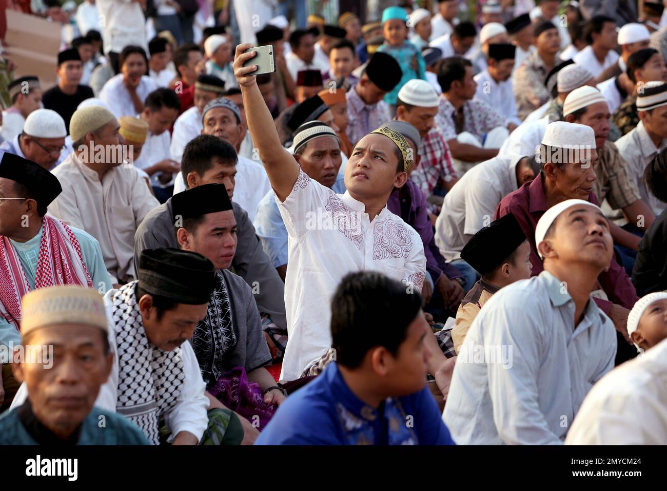An Indonesian Muslim man uses his mobile phone as he prepares for an ...