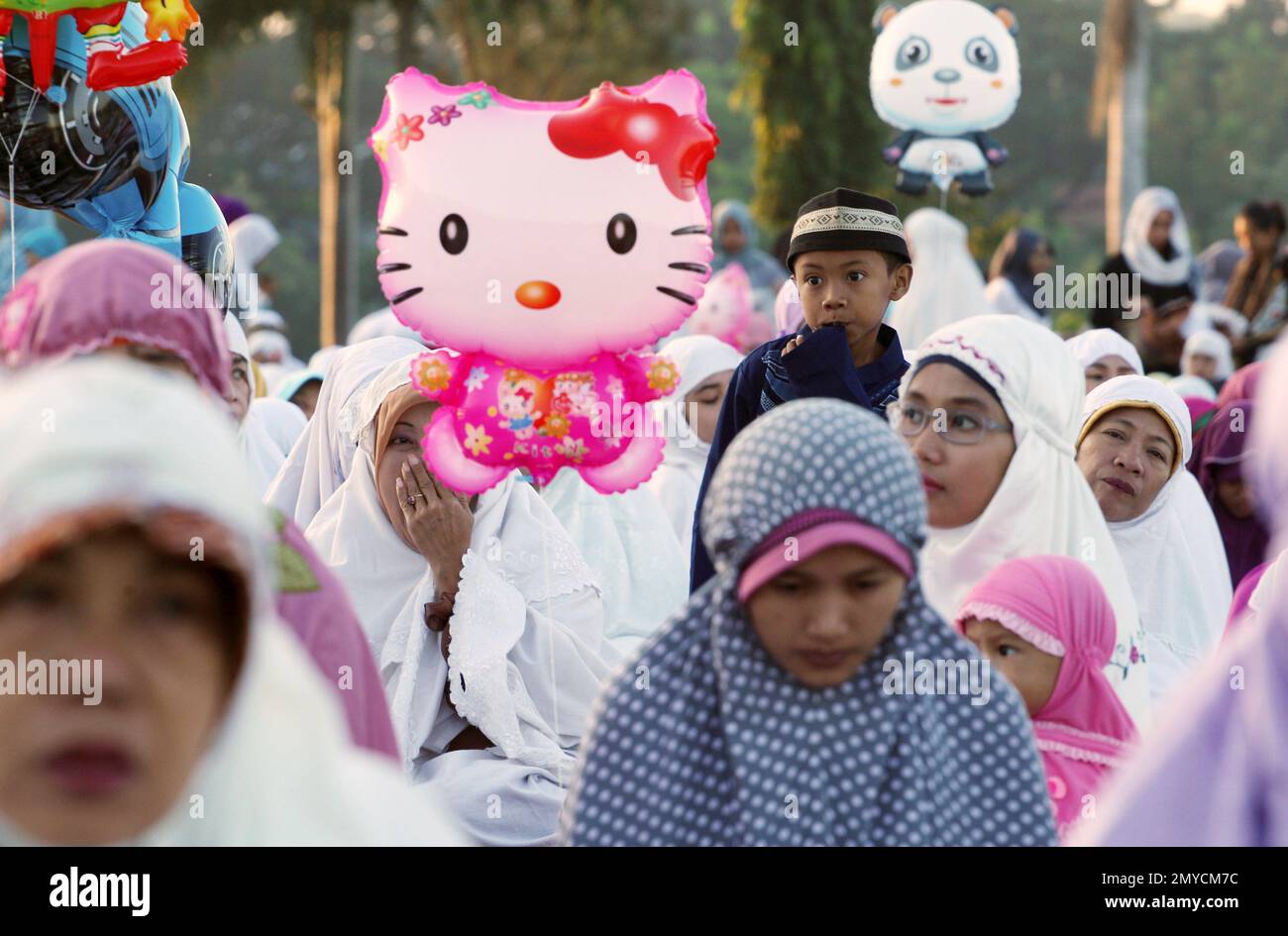 Muslim women attend an Eid al-Fitr prayer, with a balloon of cartoon ...