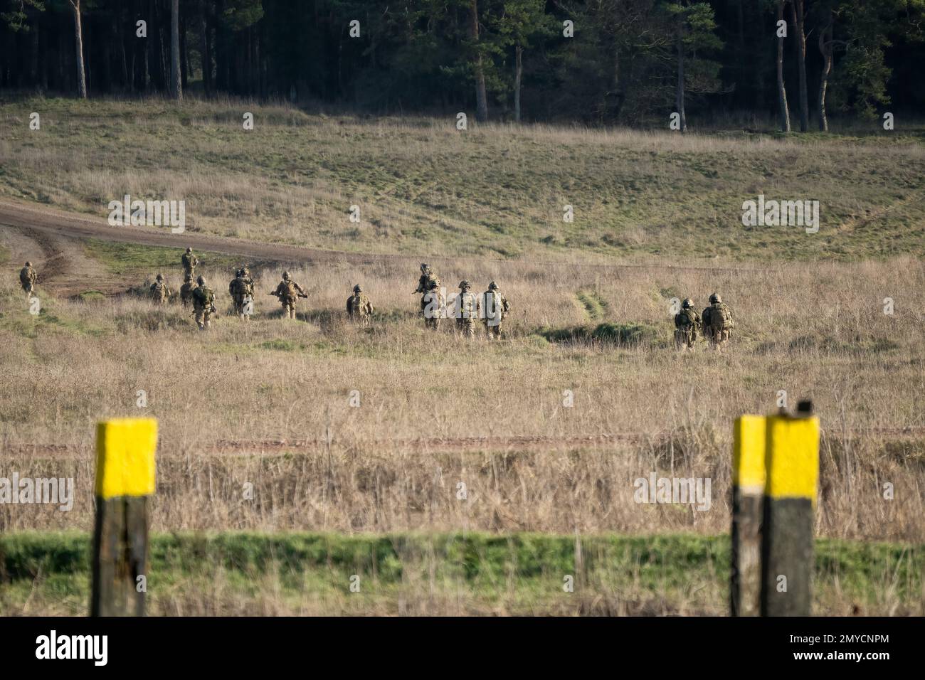 a unit of British army soldiers move across open meadowland on a ...