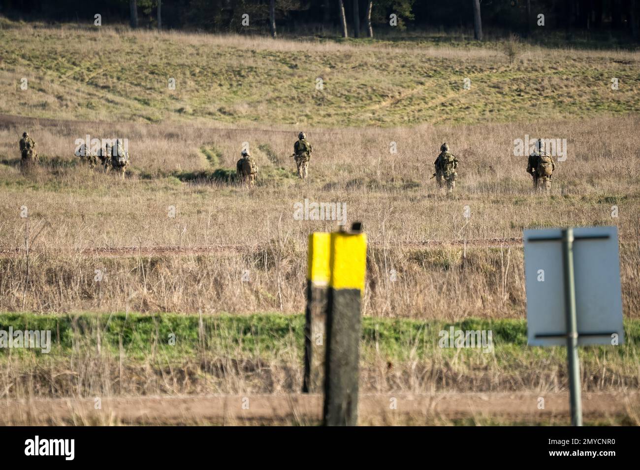 a unit of British army soldiers move across open meadowland on a ...