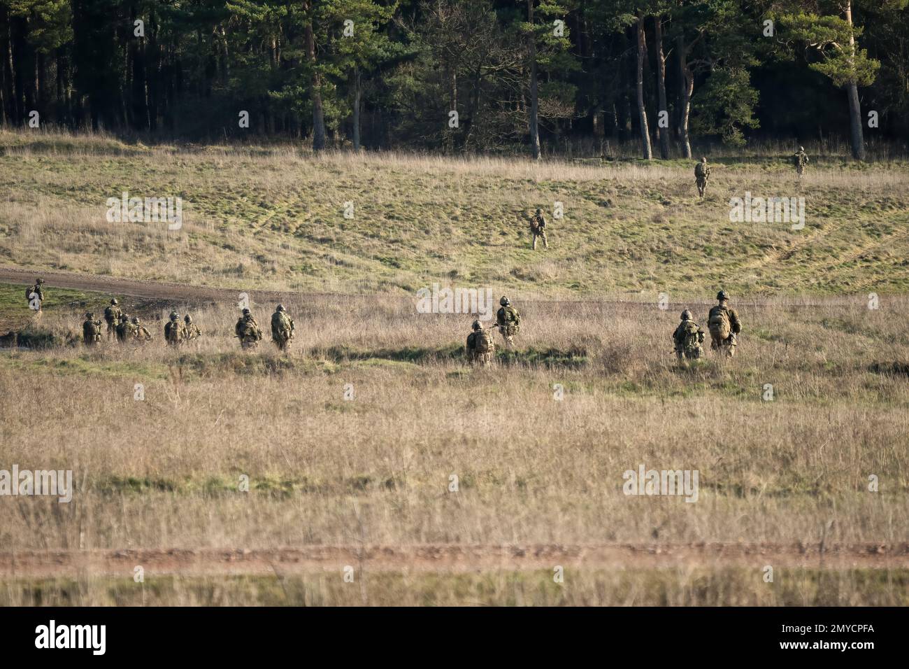 a unit of British army soldiers move across open meadowland on a ...