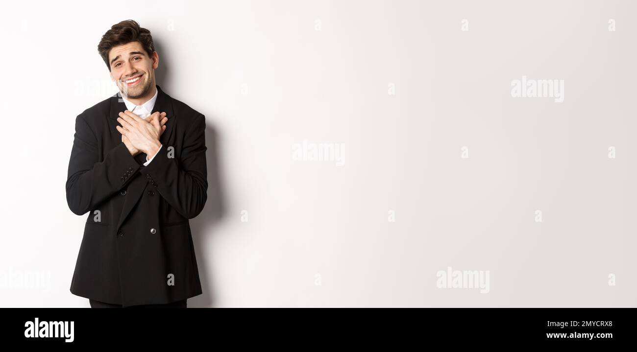 Portrait of happy and pleased handsome man in party suit, holding hands ...