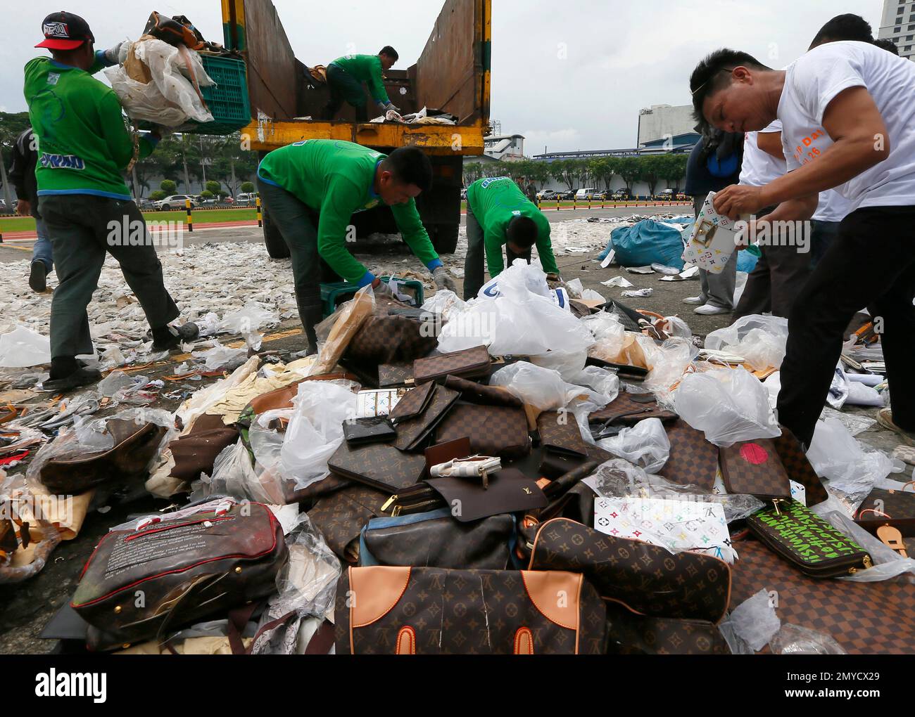 Workers cut fake handbags in a symbolic destruction of counterfeit ...