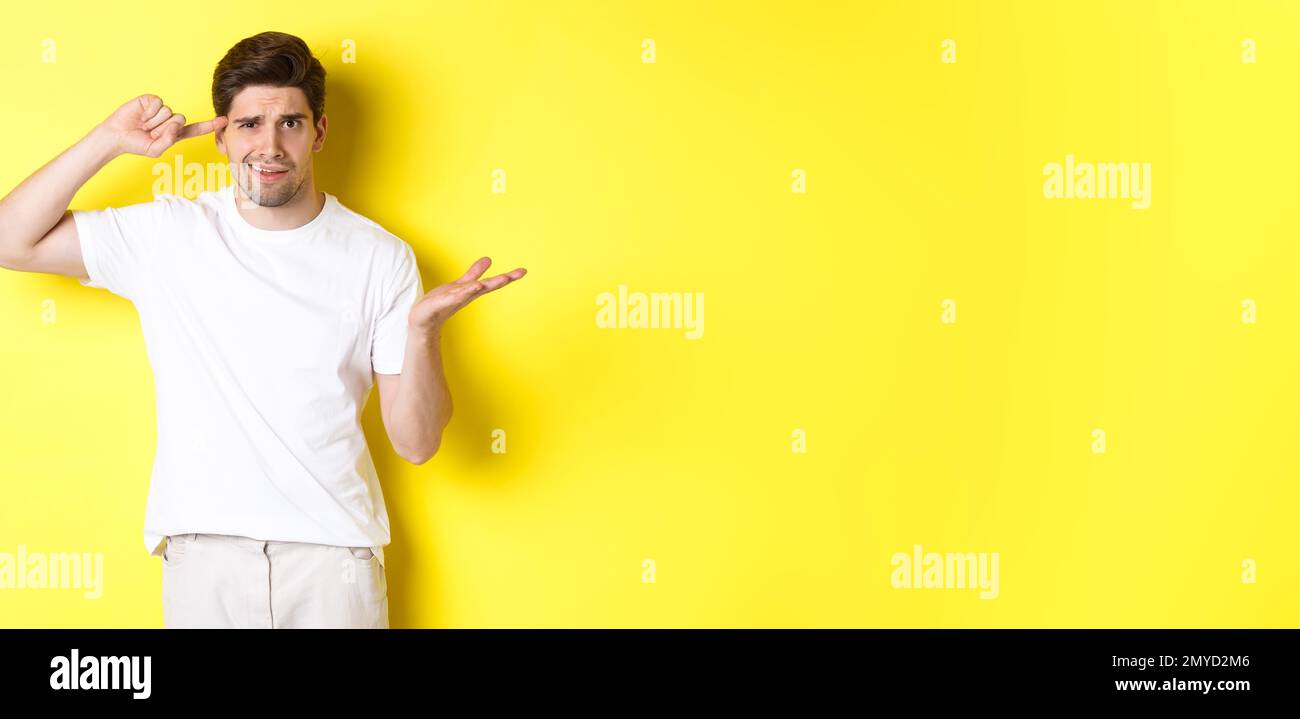 Confused and angry man pointing at head, scolding person for acting ...