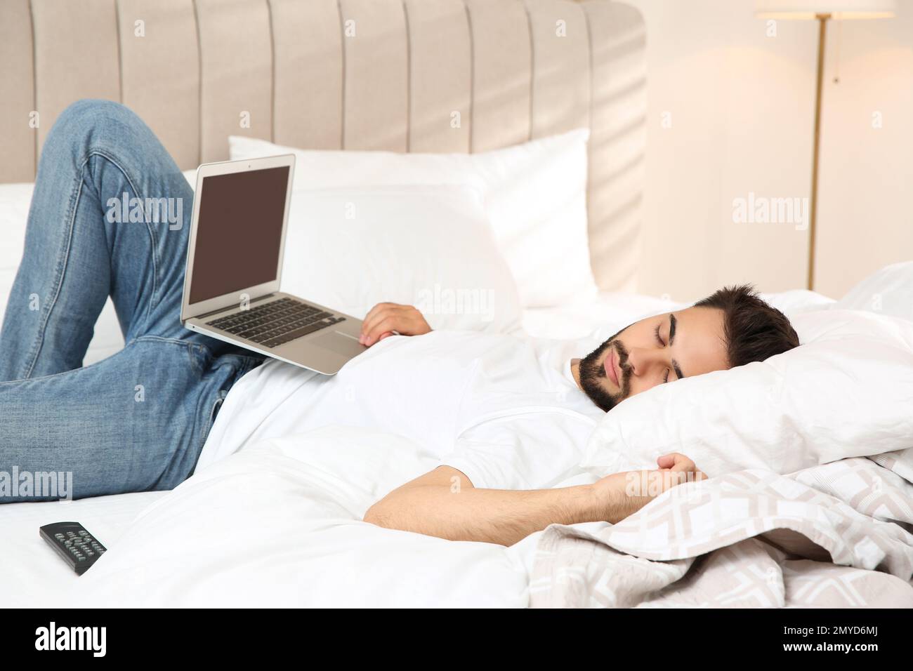 Lazy young man with laptop sleeping on bed at home Stock Photo - Alamy