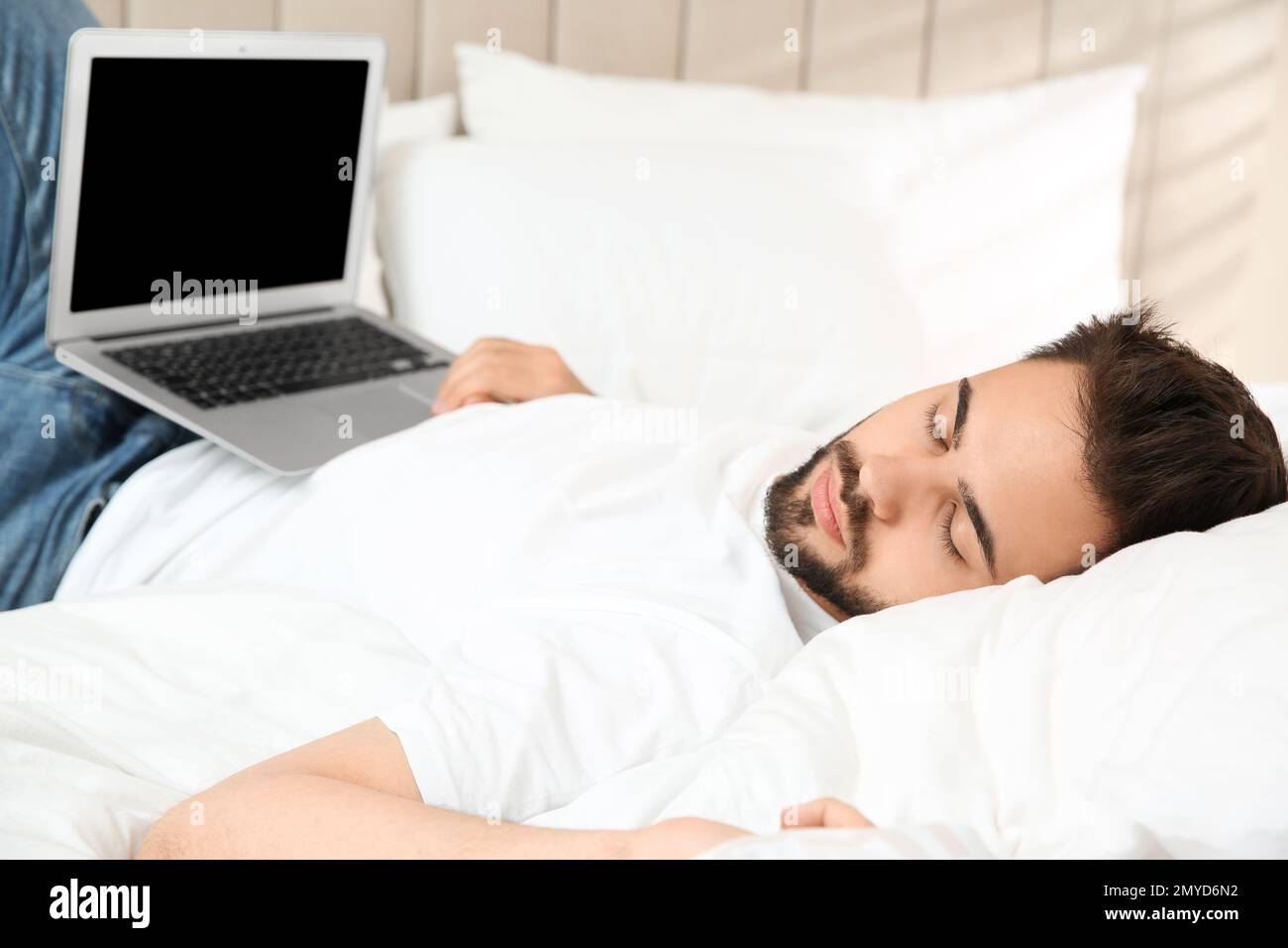 Lazy young man with laptop sleeping on bed at home Stock Photo - Alamy