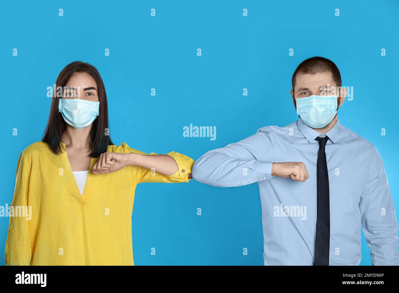 Man and woman bumping elbows to say hello on light blue background ...
