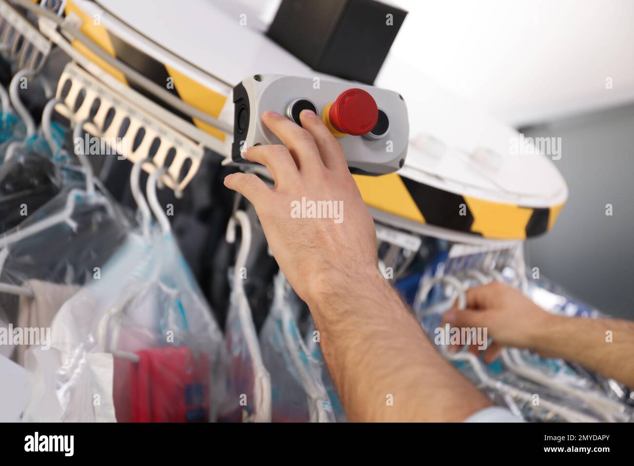 Worker pressing button on control panel of garment conveyor at modern ...
