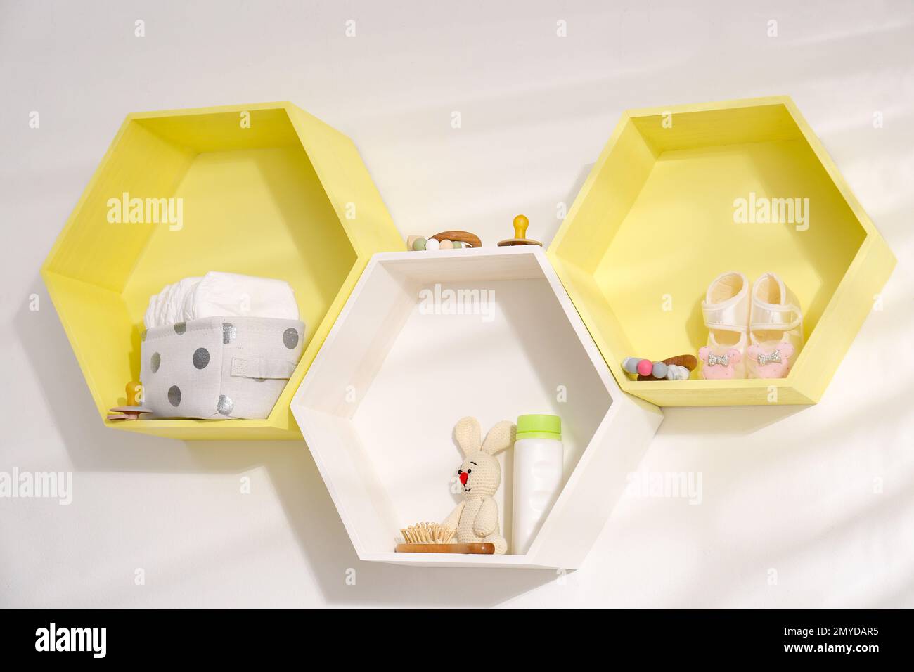 Hexagon shaped shelves with toys and child's accessories on white wall ...