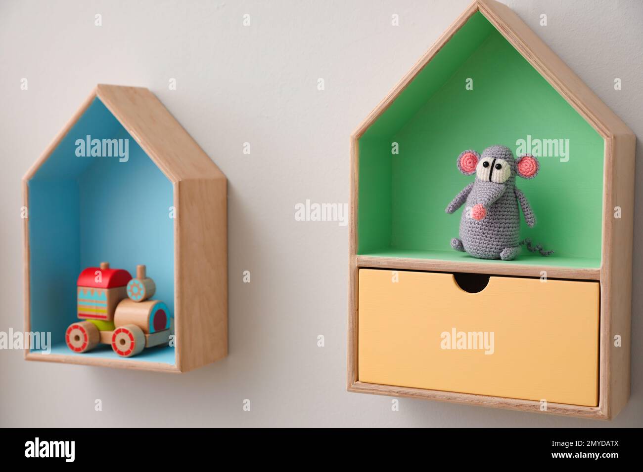Stylish house shaped shelves with toys on white wall. Baby room ...