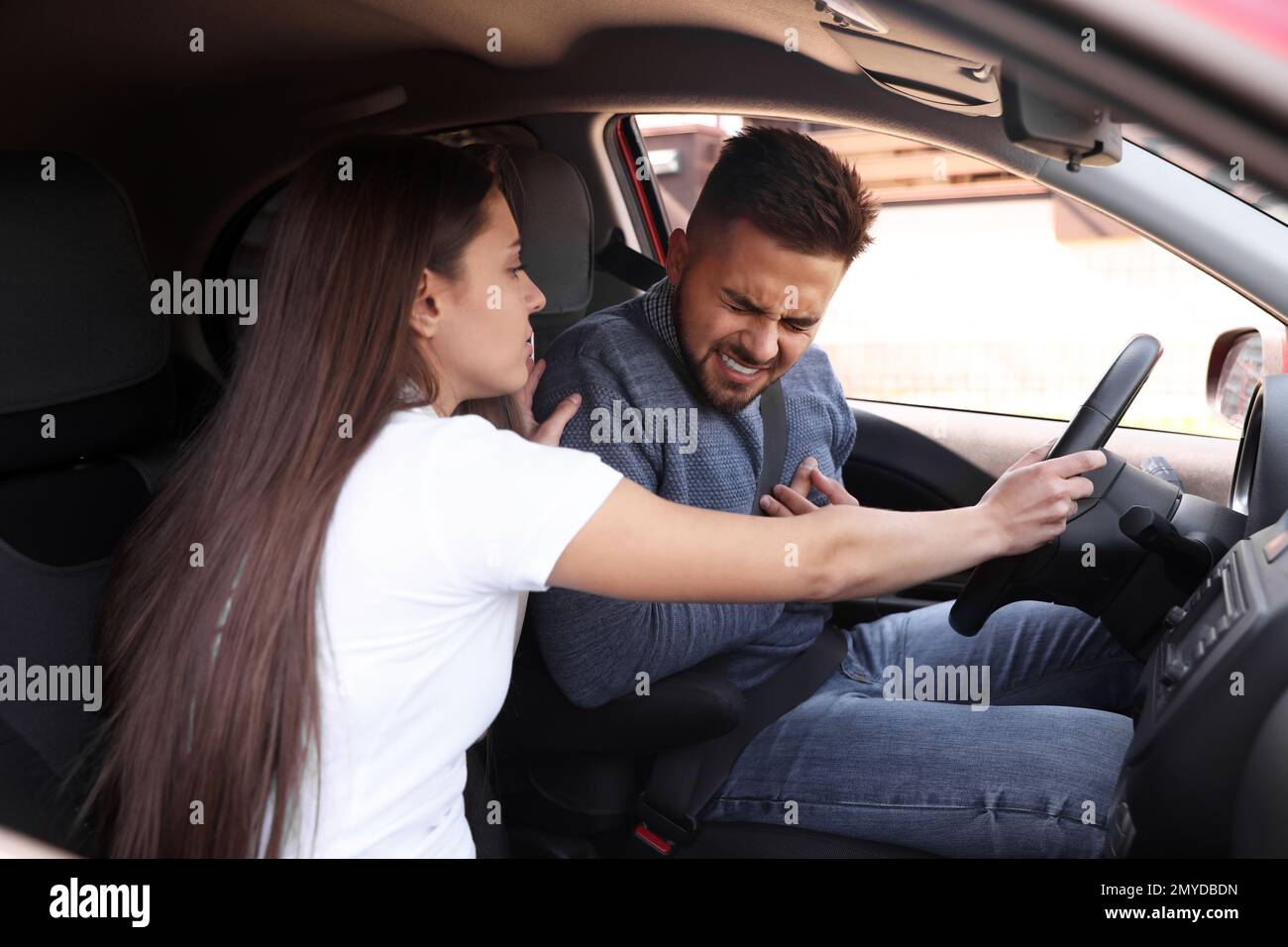 Woman holding steering wheel while driver suffering from heart attack in car Stock Photo - Alamy