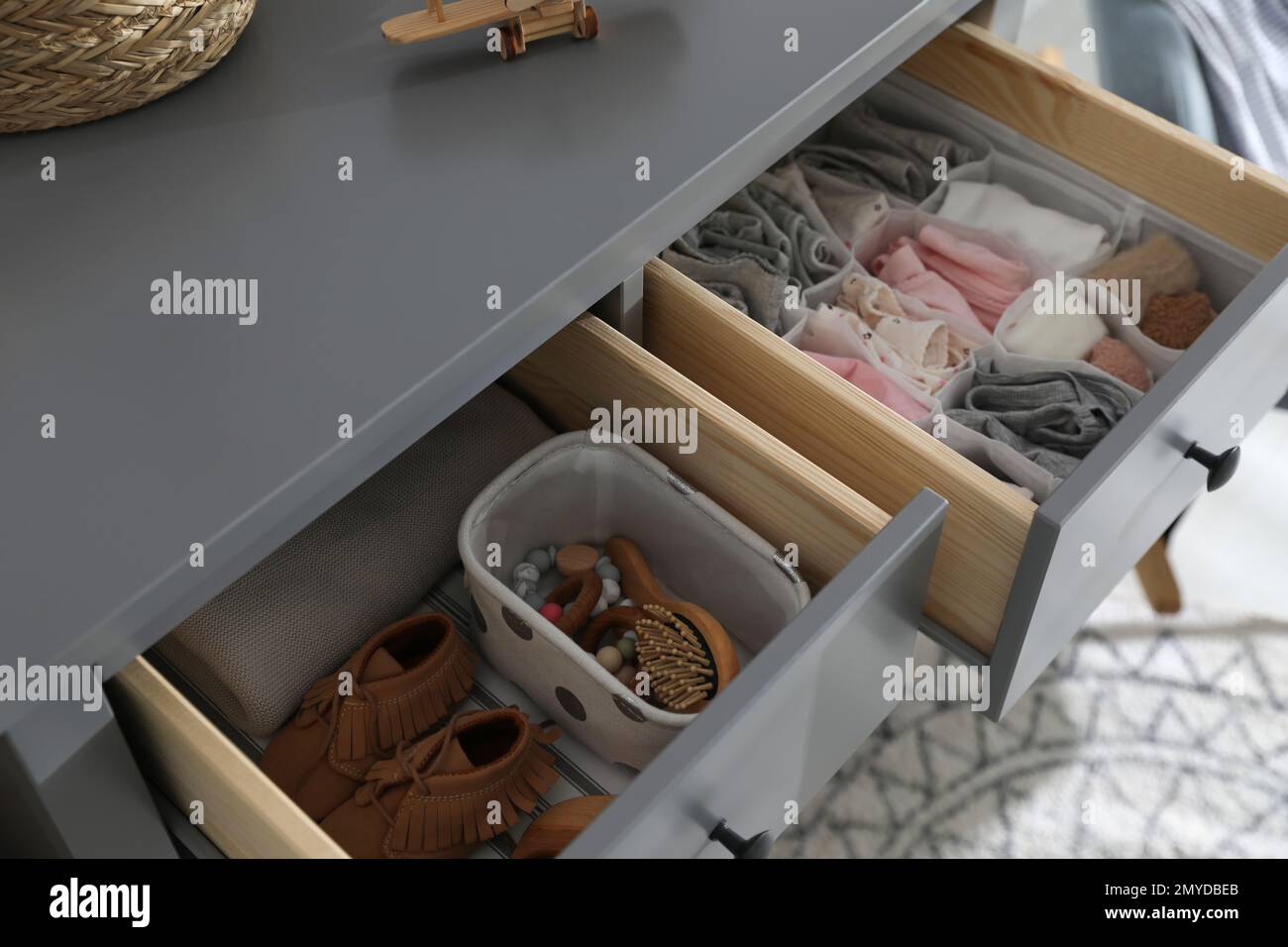 Open cabinet drawers with clothes and different items in child room ...