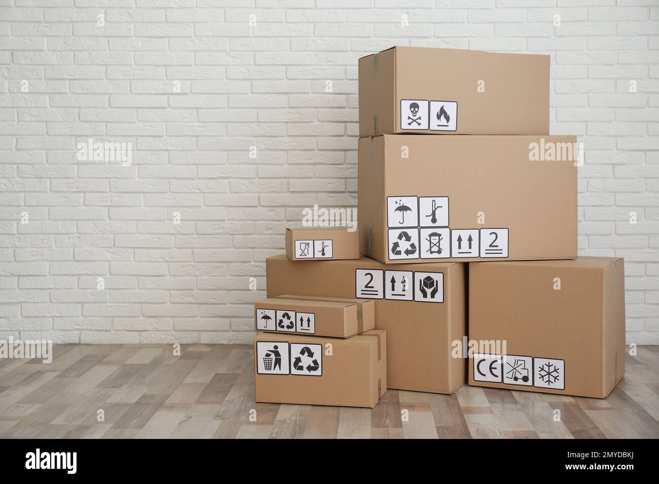 Cardboard boxes with different packaging symbols on floor near white ...