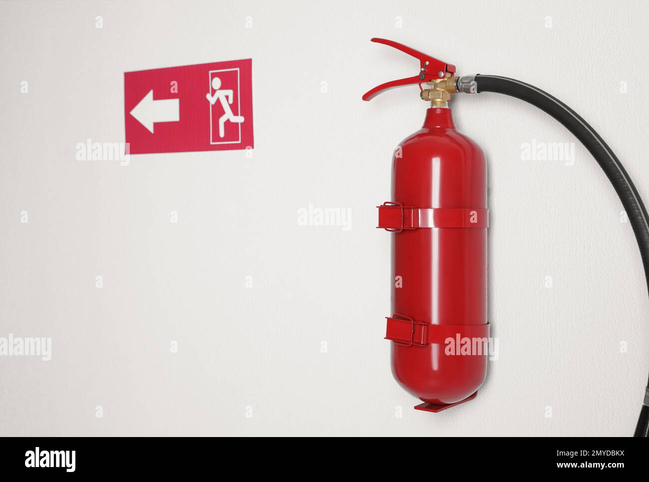 Fire extinguisher and emergency exit sign on white wall Stock Photo - Alamy