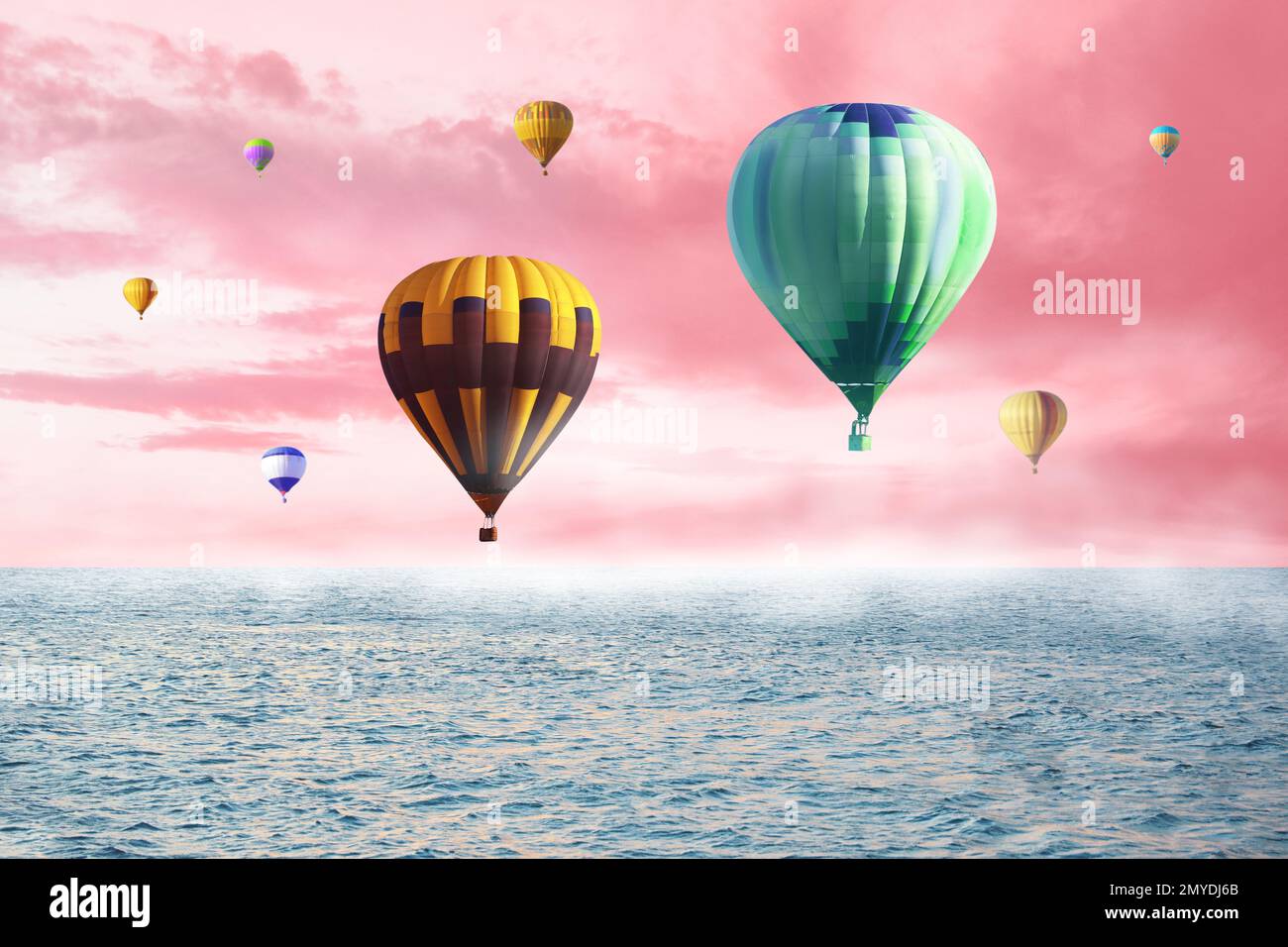 Dream world. Hot air balloons in pink sky with clouds over misty sea ...