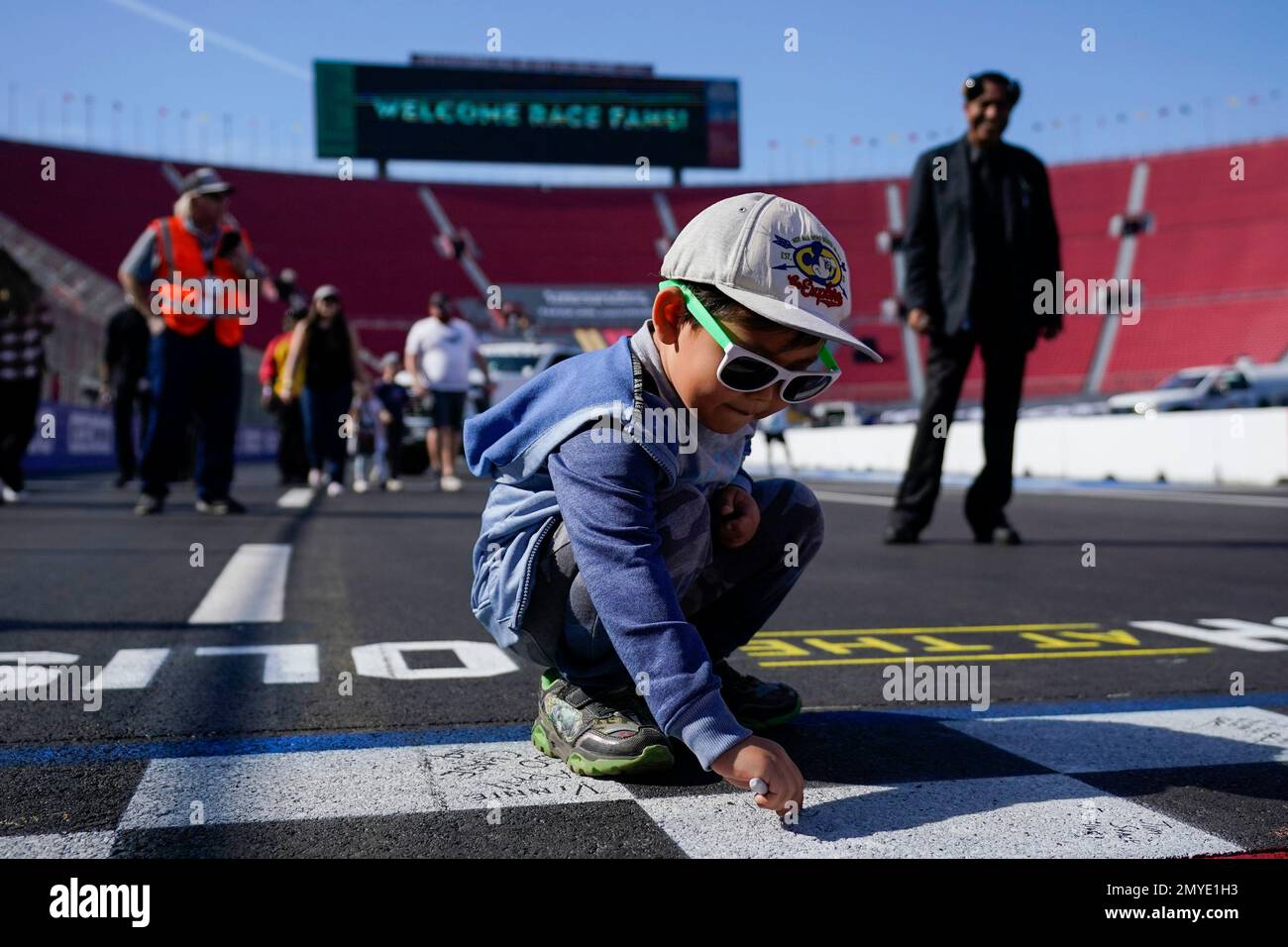 A young fan signs his name on the finish line ahead of practice ...