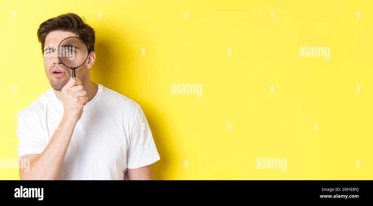 Man looking through magnifying glass with serious and thoughtful look ...