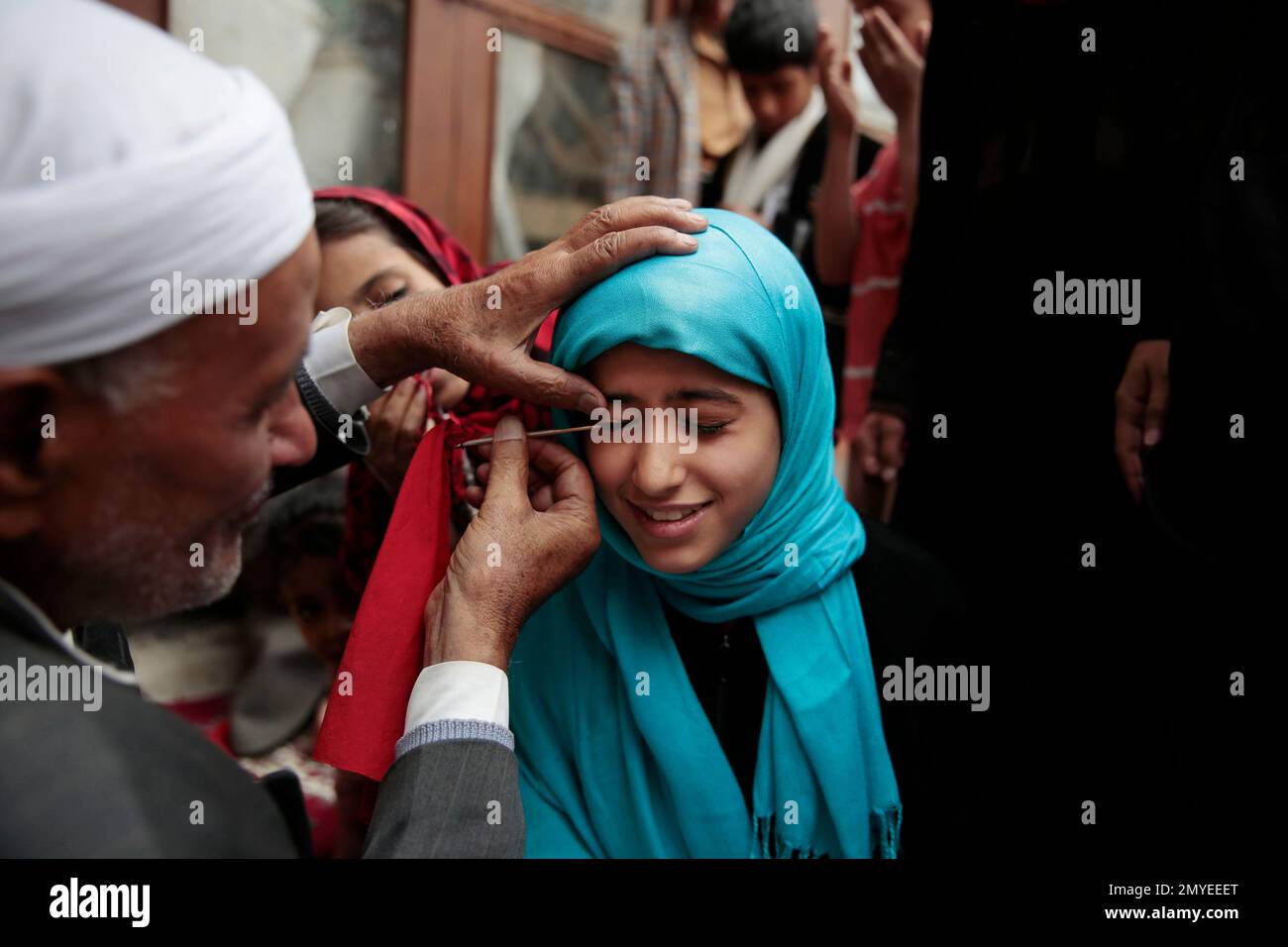 A man applies cosmetic kohl on a girl's eyelid during the holy month of ...