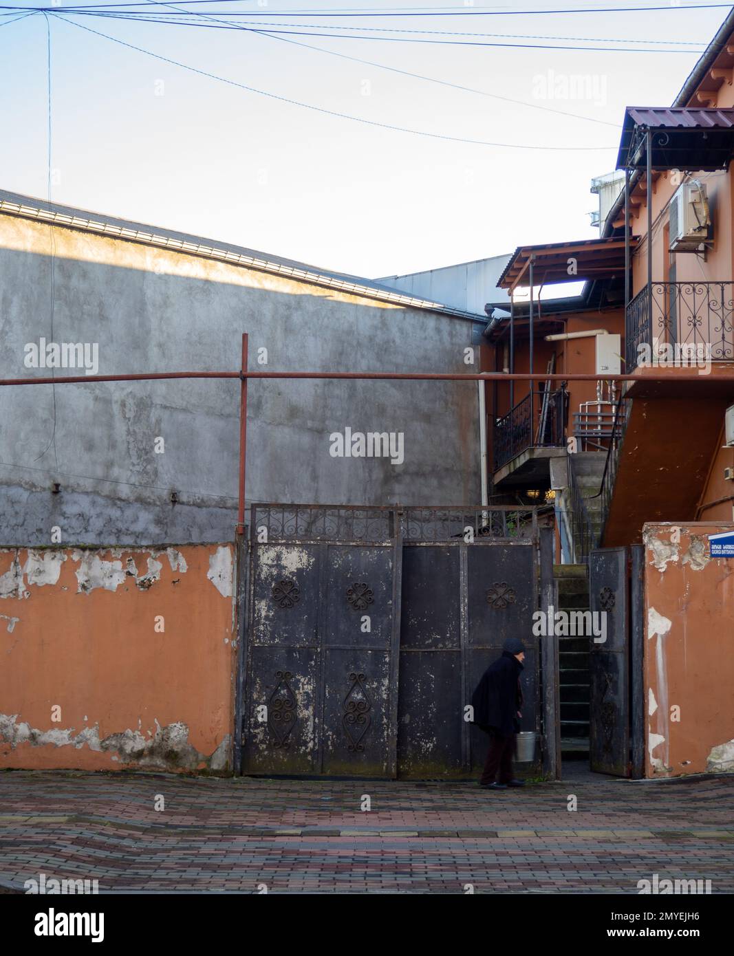Man in the yard in the old district. Facade of an old house. Shabby ...