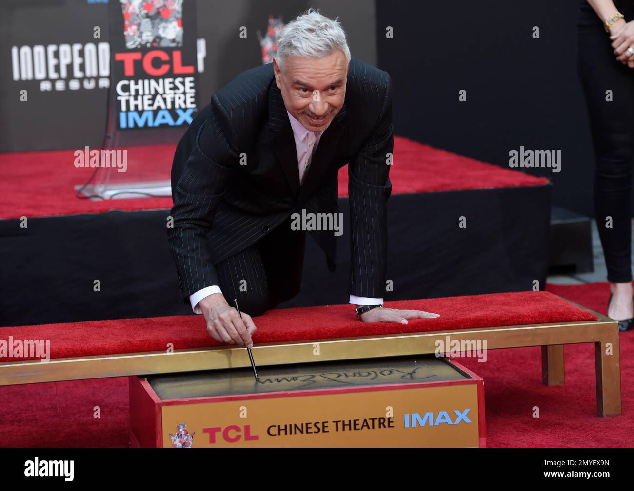 Roland Emmerich signs his name in cement during a handprint and ...