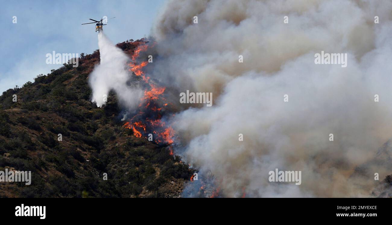A helicopter drops water on wildfire on a hill near Azusa, Calif ...