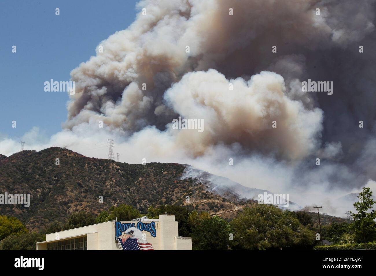 Smoke from a wildfire rises from a hillside behind the Royal Oaks ...