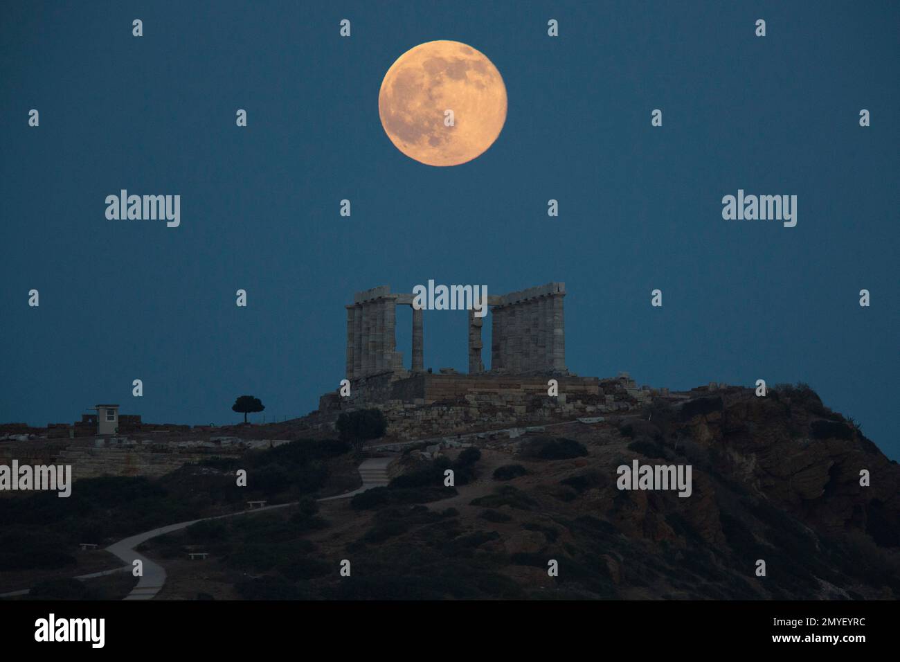The full moon rises behind above the ancient marble Temple of Poseidon ...