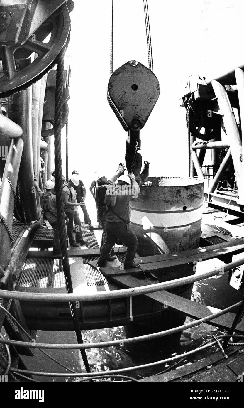 Workmen lower a 625-foot steel piling into the Gulf of Mexico to nail ...