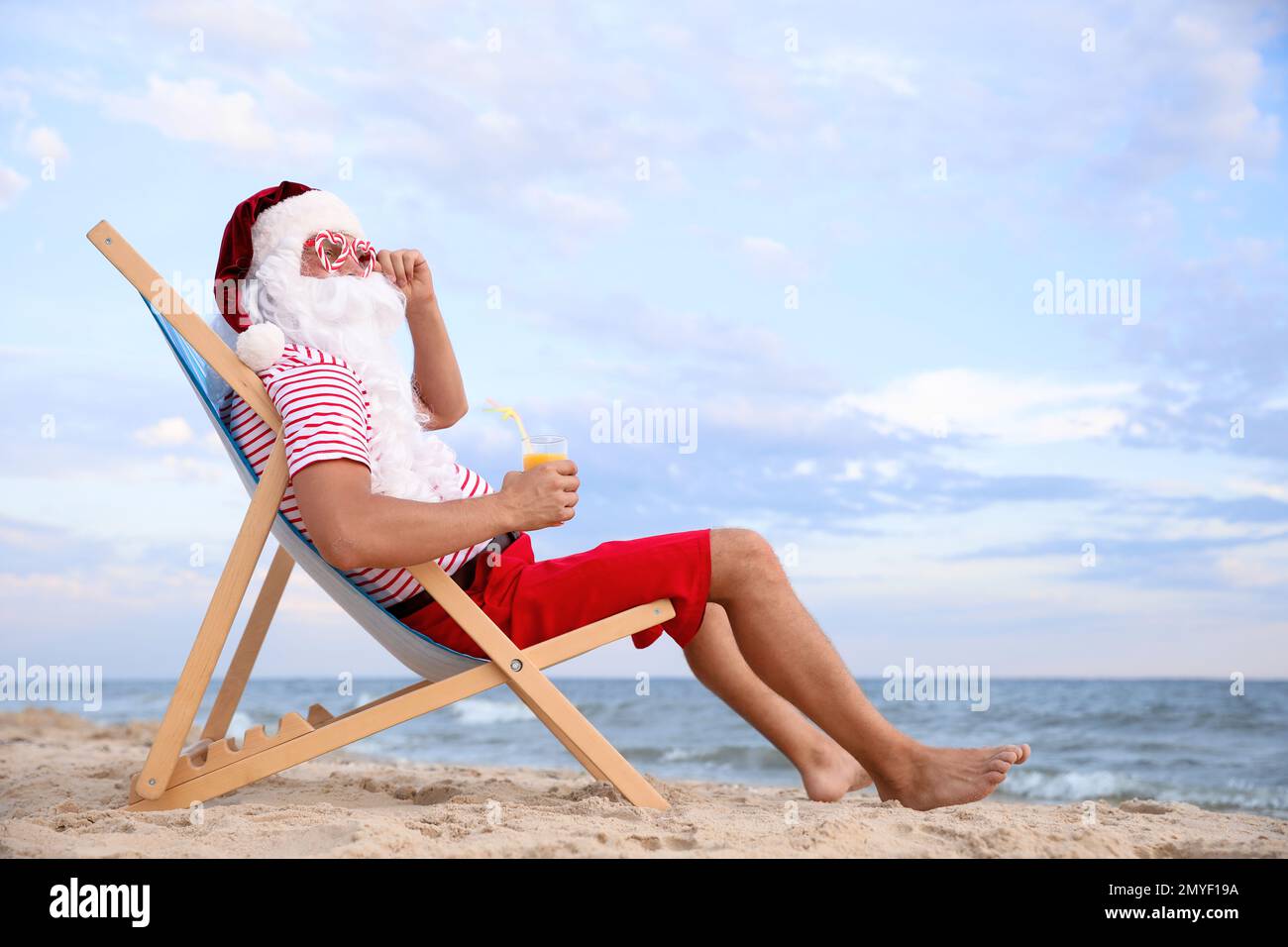 Santa Claus with cocktail relaxing in chair on beach, space for text ...