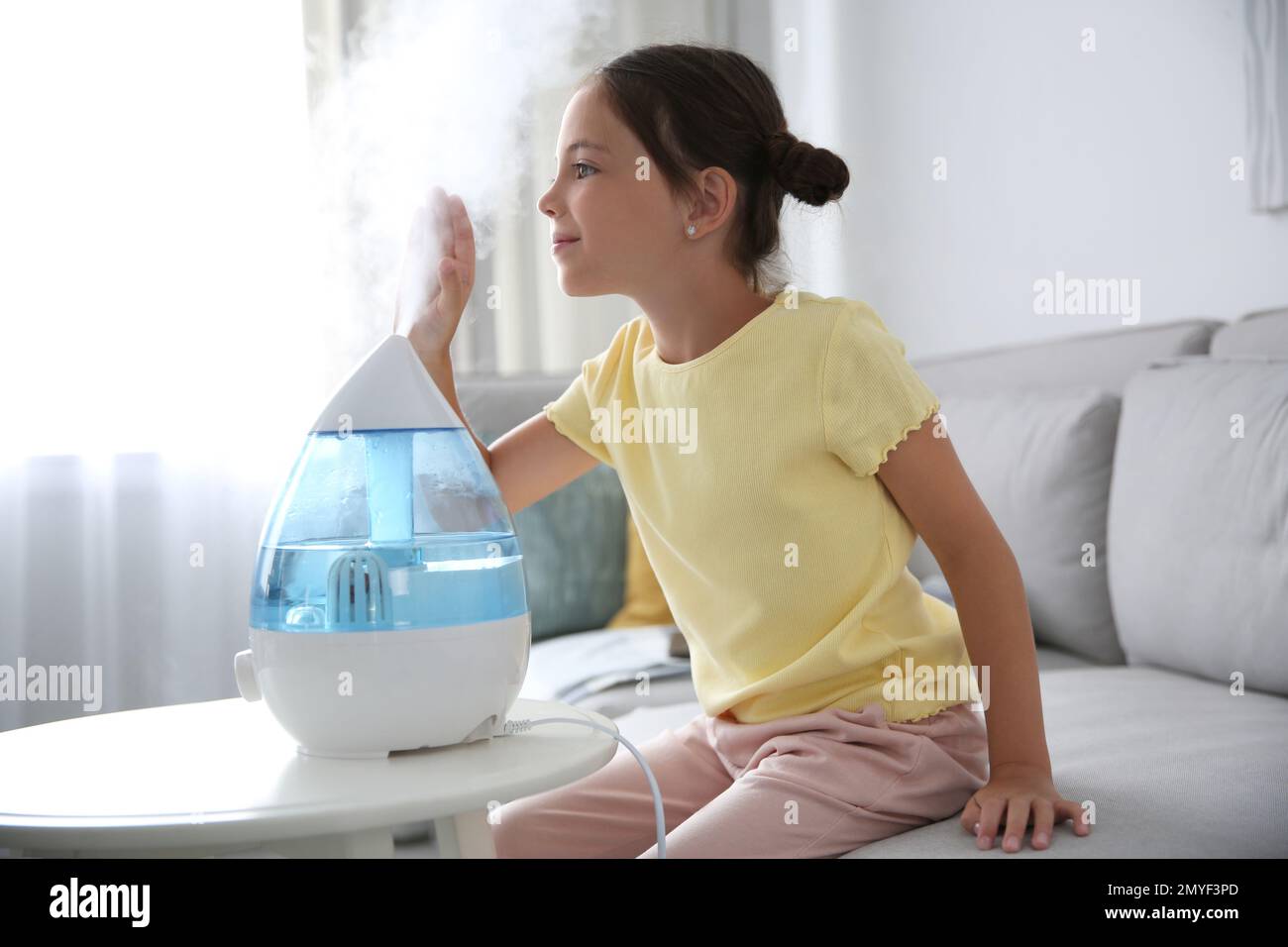 Little girl near modern air humidifier at home Stock Photo - Alamy