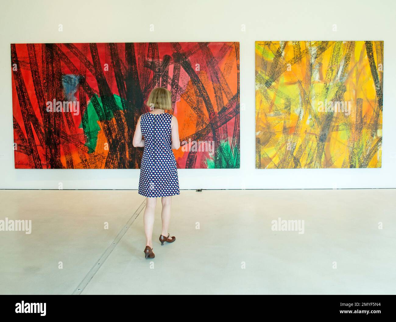 A woman walks in front of the paintings 'Without title' (1960), left, and 'Come closer' (1960 ...