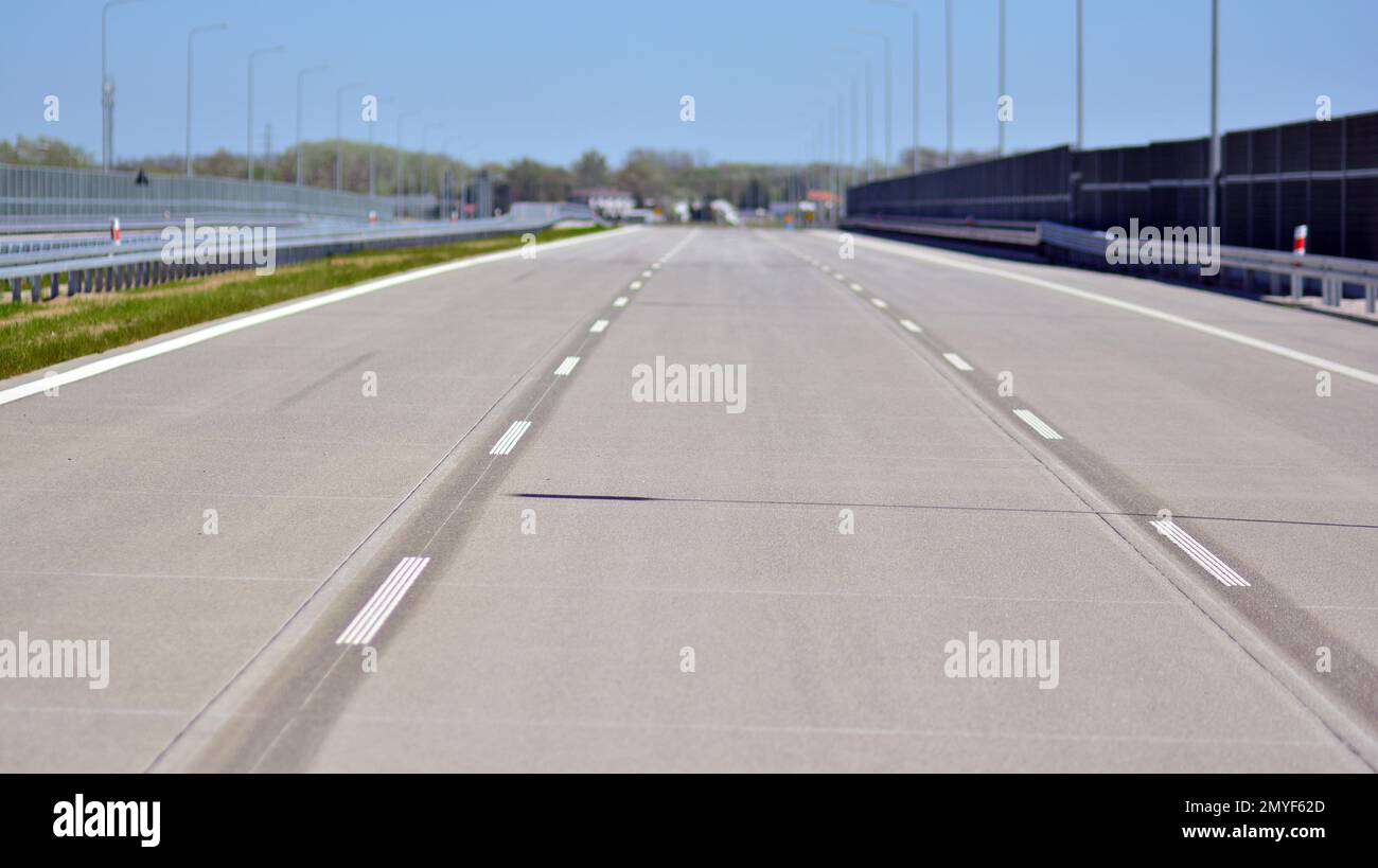 Straight modern concrete motorway with bright road marking ...