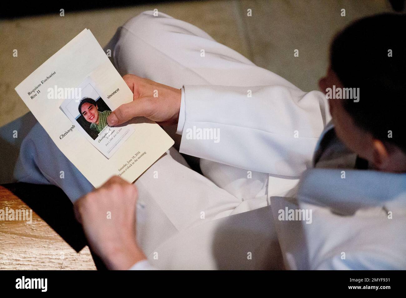 A mourner looks through a program before the funeral service for ...