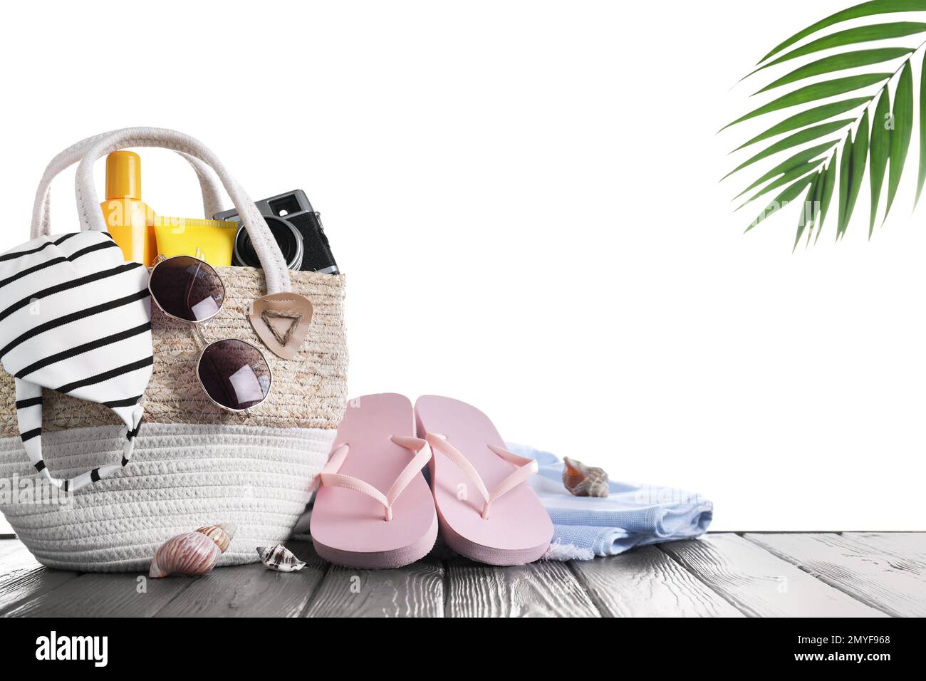 Bag with different beach objects on grey wooden table against white ...