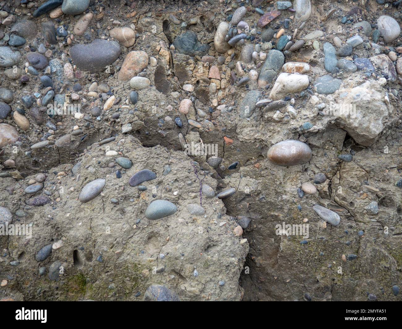 Layers of earth on a beach made of pebbles. Soil cut. Cobblestones and ...