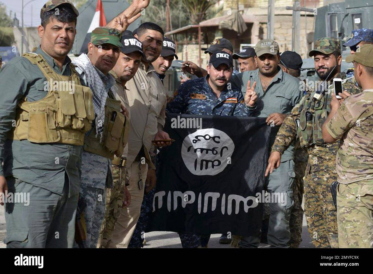Iraqi security forces celebrate as they pose with a flag of the Islamic ...